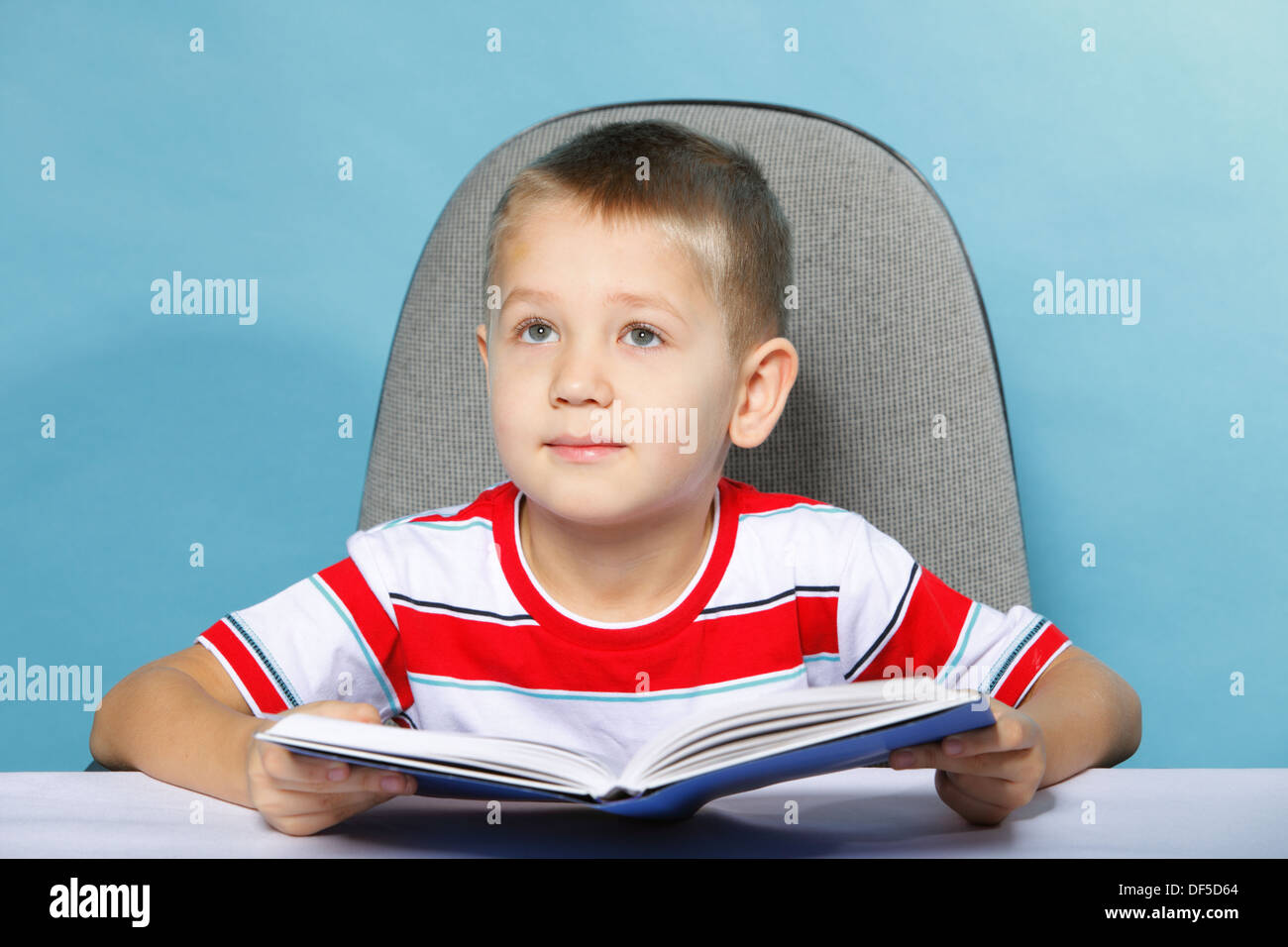 Young boy reading a book, child kid on blue background holding an open ...