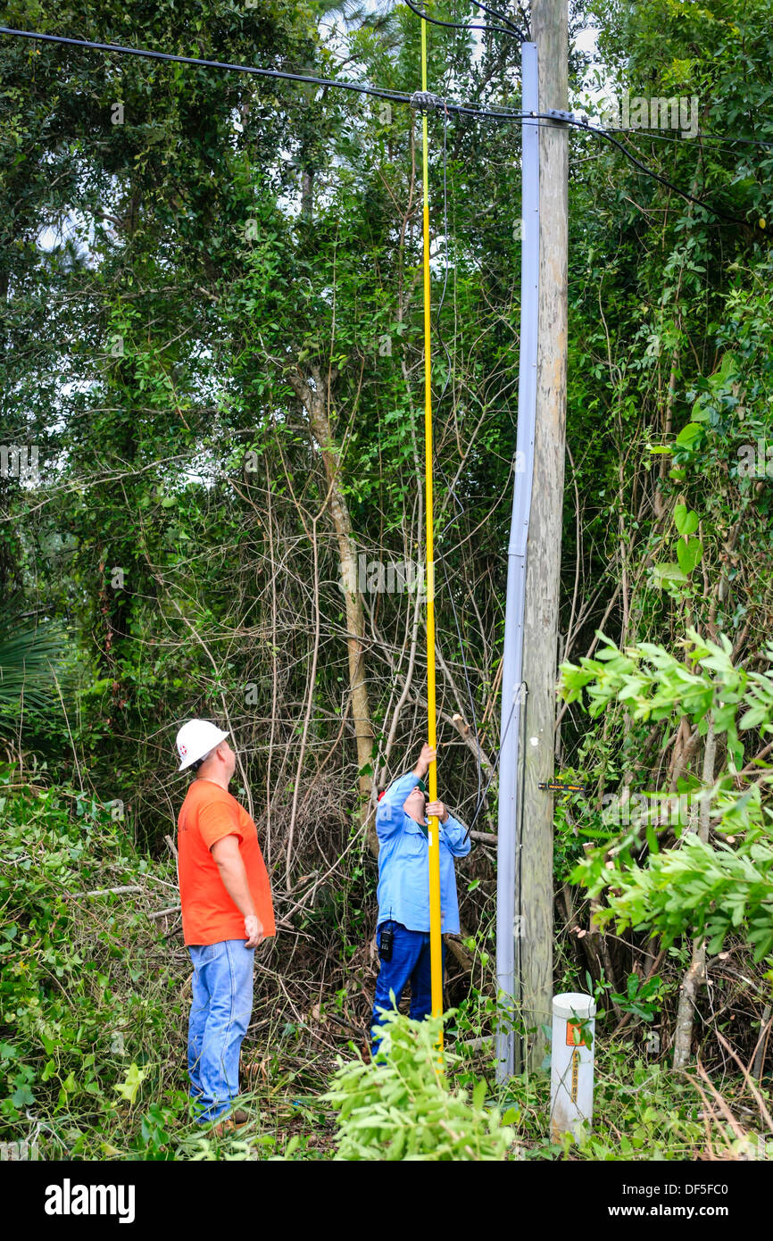 An electricity company employee uses a pole to replace a fuse to the ...