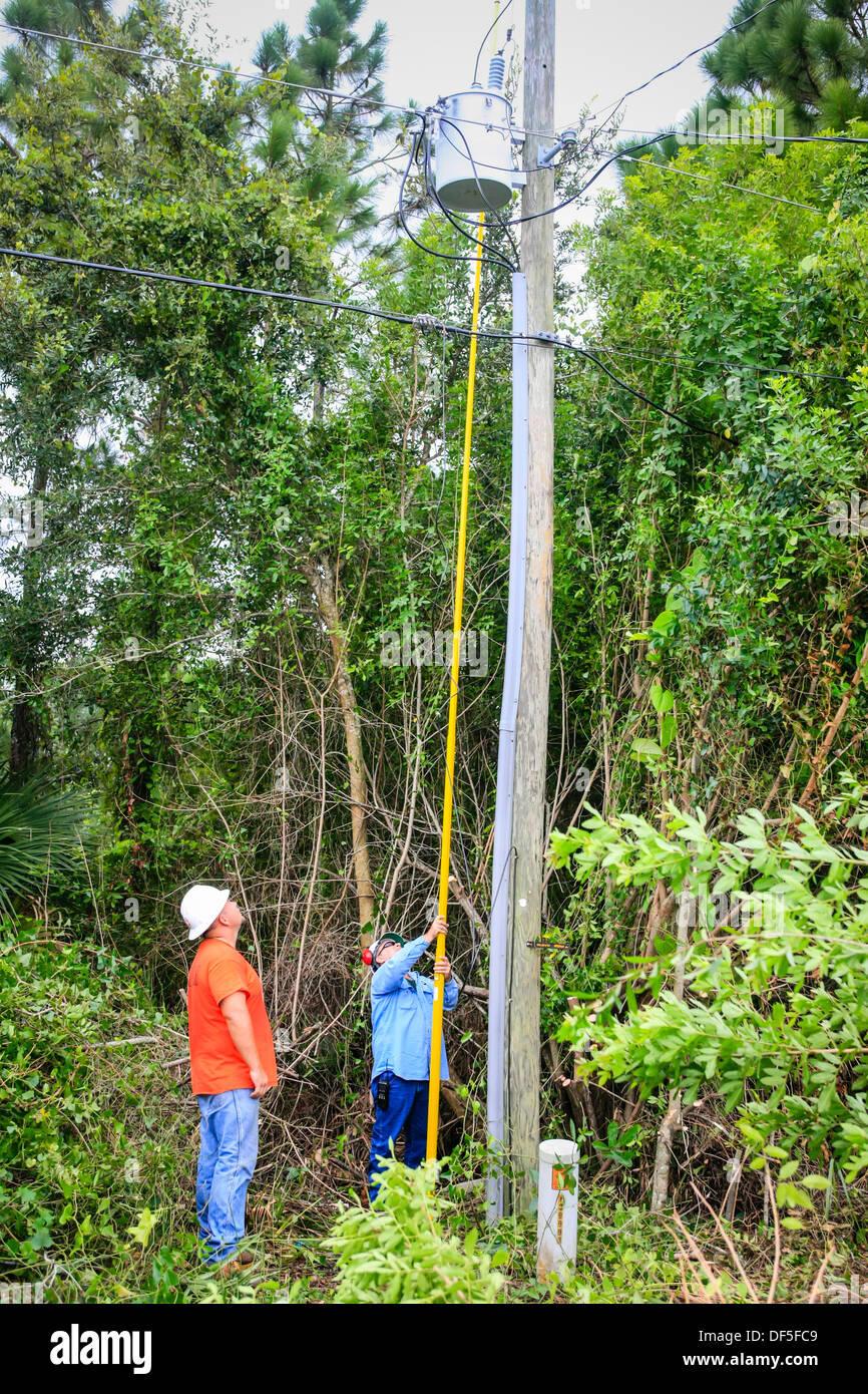 An electricity company employee uses a pole to replace a fuse to the ...
