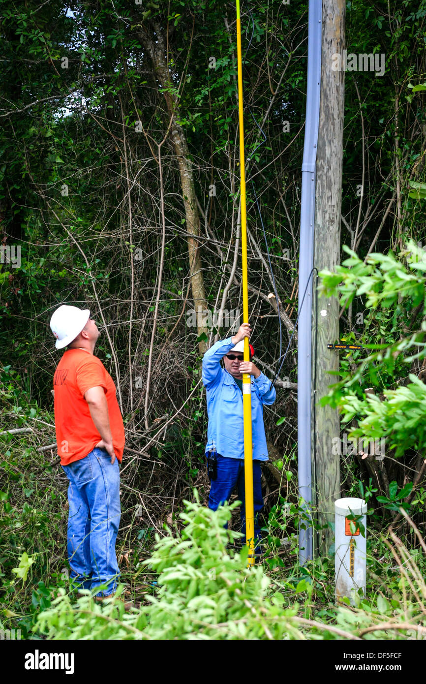 An electricity company employee uses a pole to replace a fuse to the ...