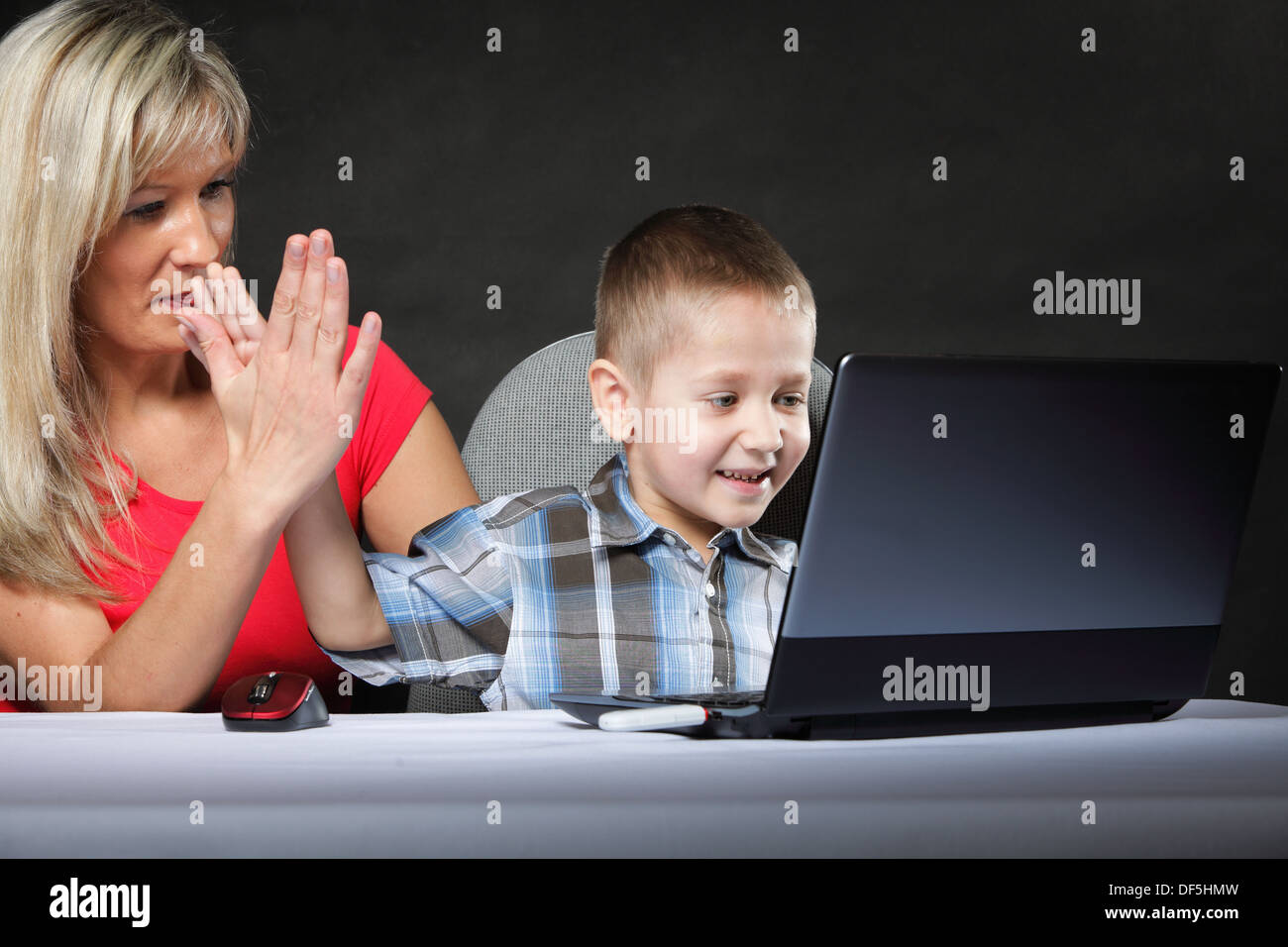 mother with son together looking on the laptop computer black ...