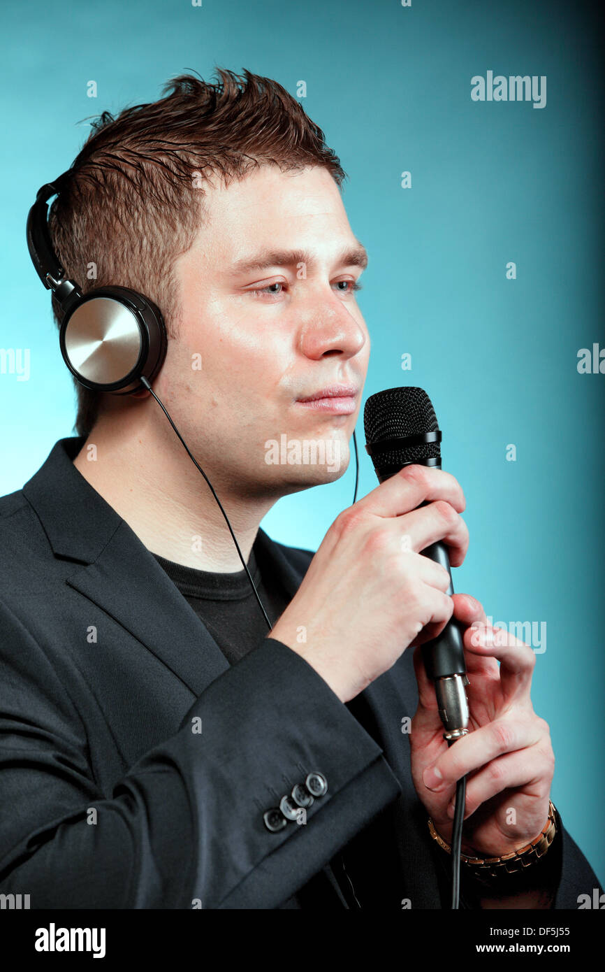 Young man singing into microphone. Happy karaoke signer studio shot ...