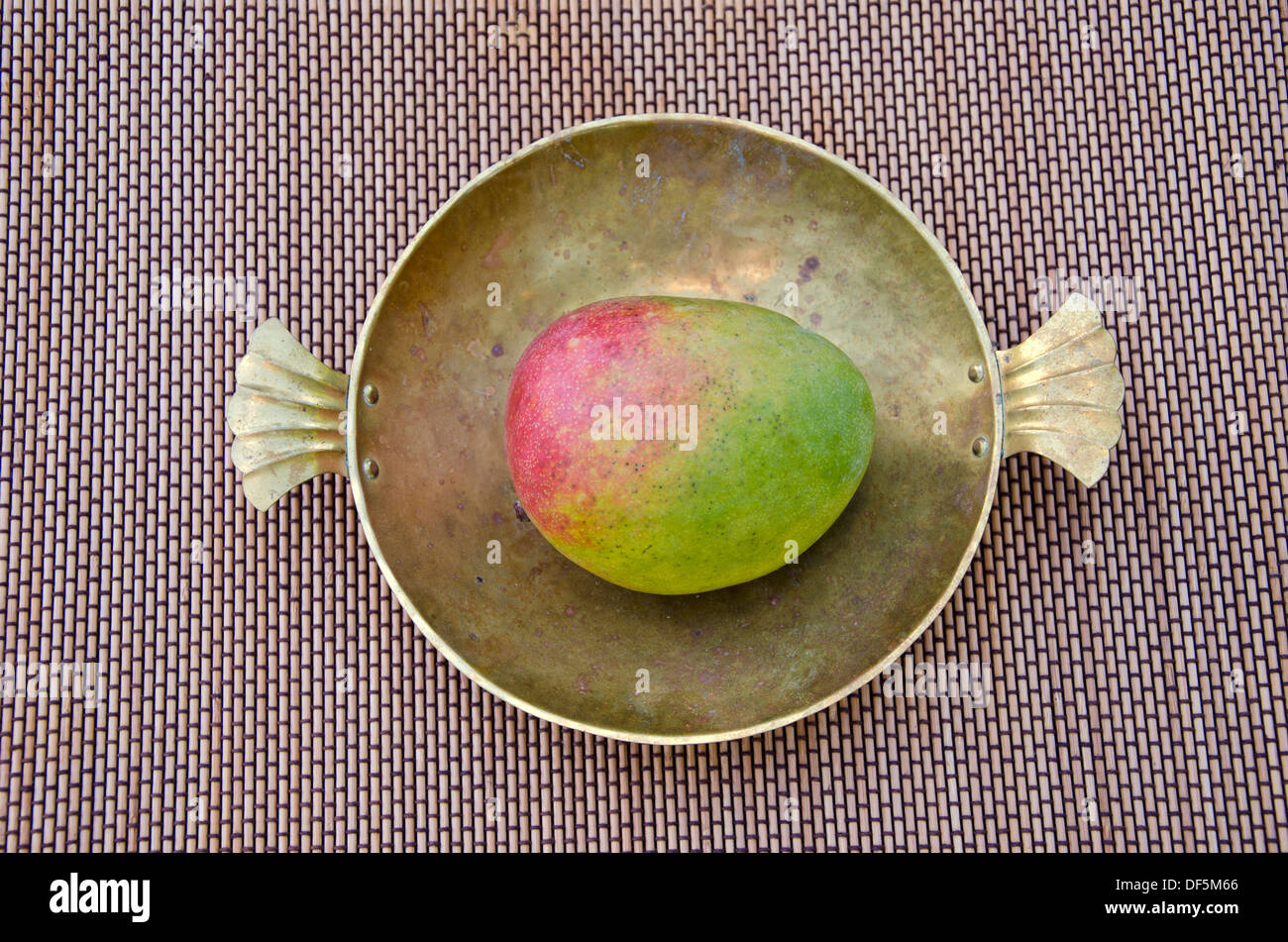 ripe sweet mango fruit in ancient brass plate on wooden background ...