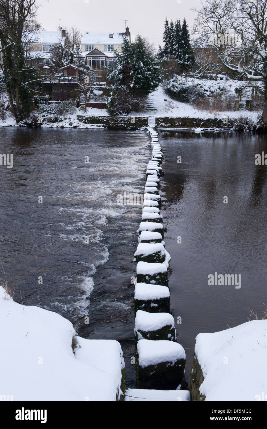 Cold winter scene with snow-covered riverside houses & stepping stones ...