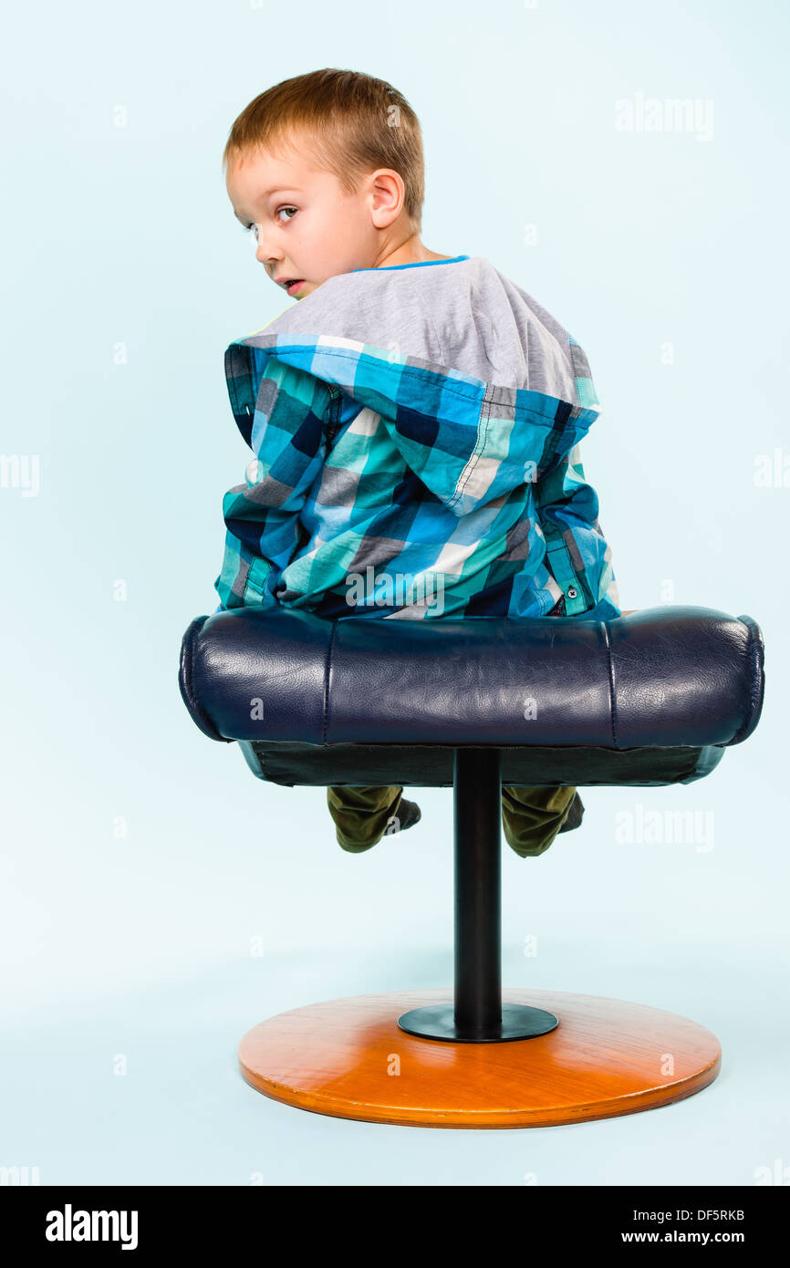 Little boy on posing with a footstool, studio shot and light blue ...