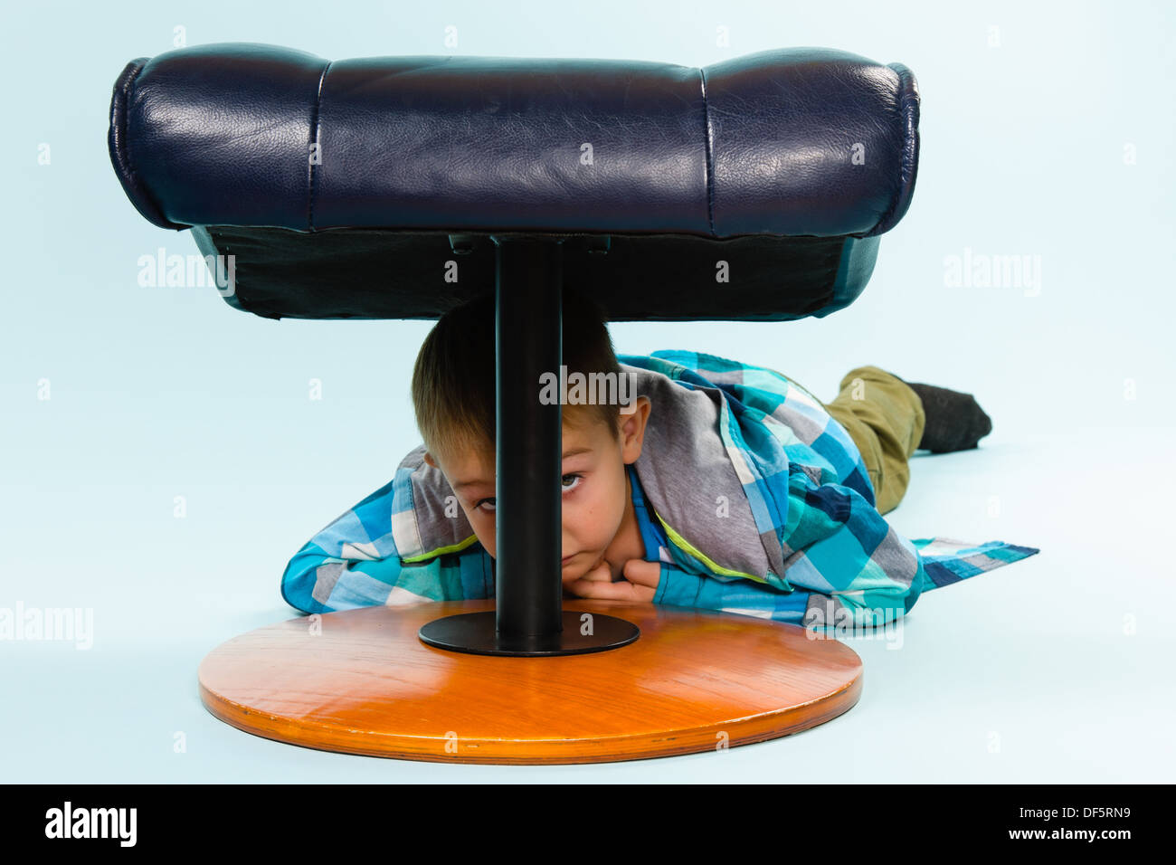 Little boy on posing with a footstool, studio shot and light blue ...
