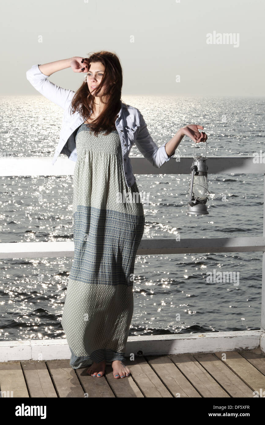 Full length young woman on pier with a oil kerosene lamp. Concept ...