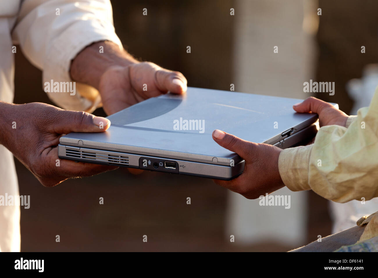 India, Rajasthan, Jodhpur, tribesman's hand receiving laptop from young ...