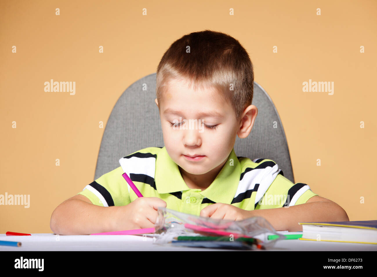 little boy drawing with color pencils on orange background Stock Photo ...