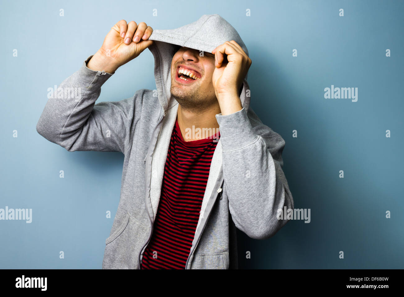 Young smiling man hiding his face under his hooded top Stock Photo - Alamy
