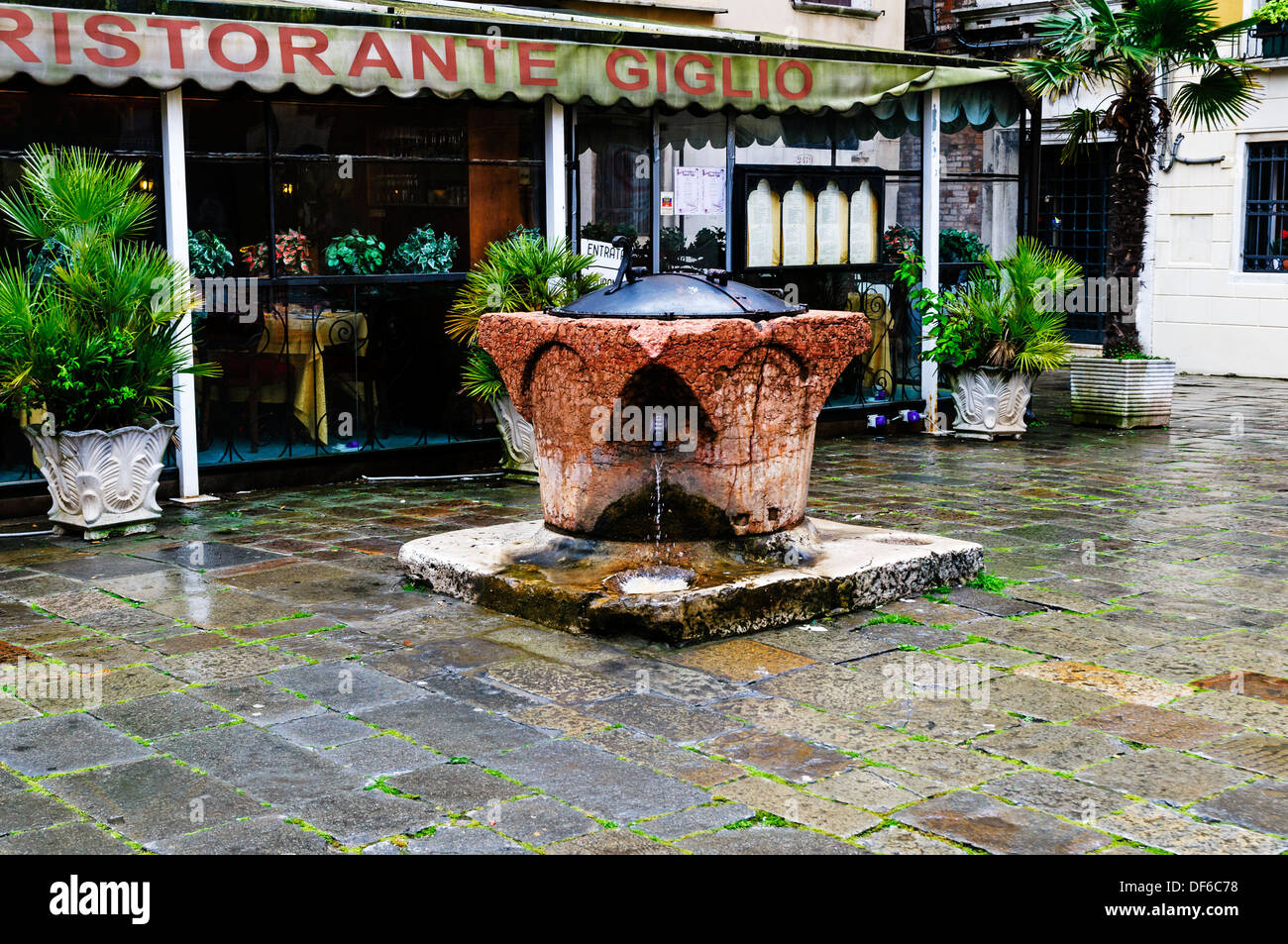 Water flows from a cup shaped fountain standing on the patio of a ...