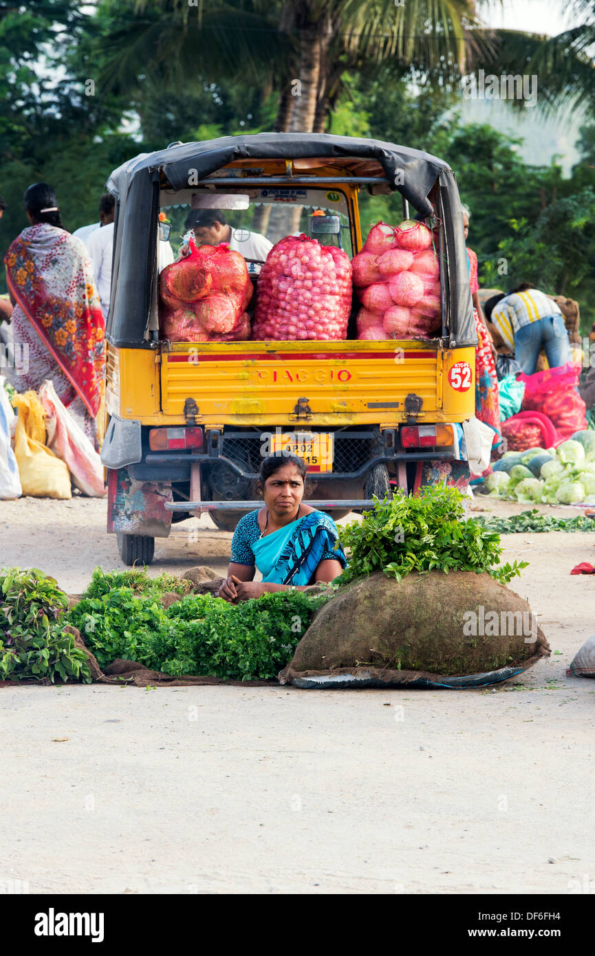 Indian woman selling herbs and leaf vegetables from sacks at a street ...