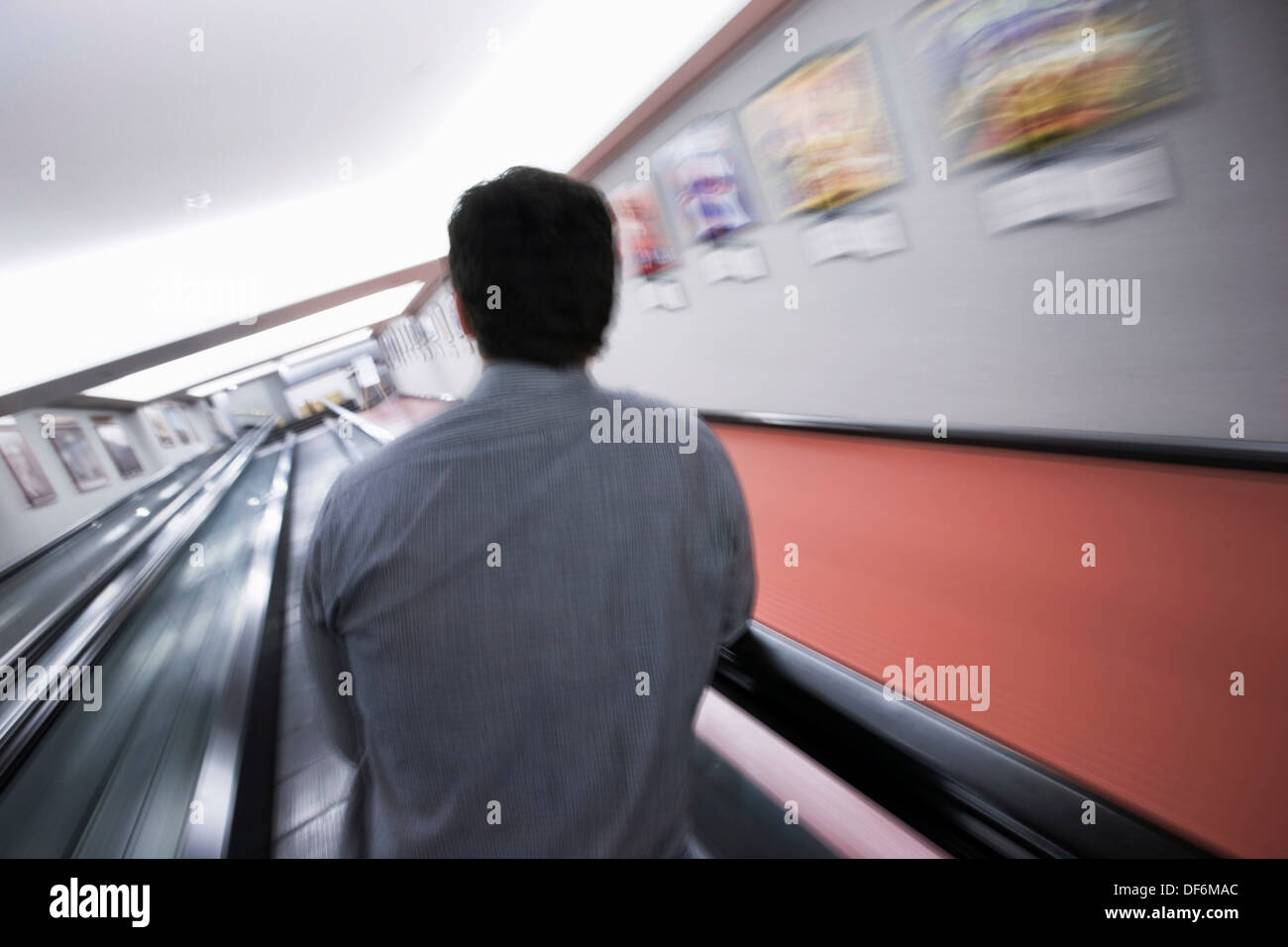 Young man standing on a moving walkway Stock Photo - Alamy