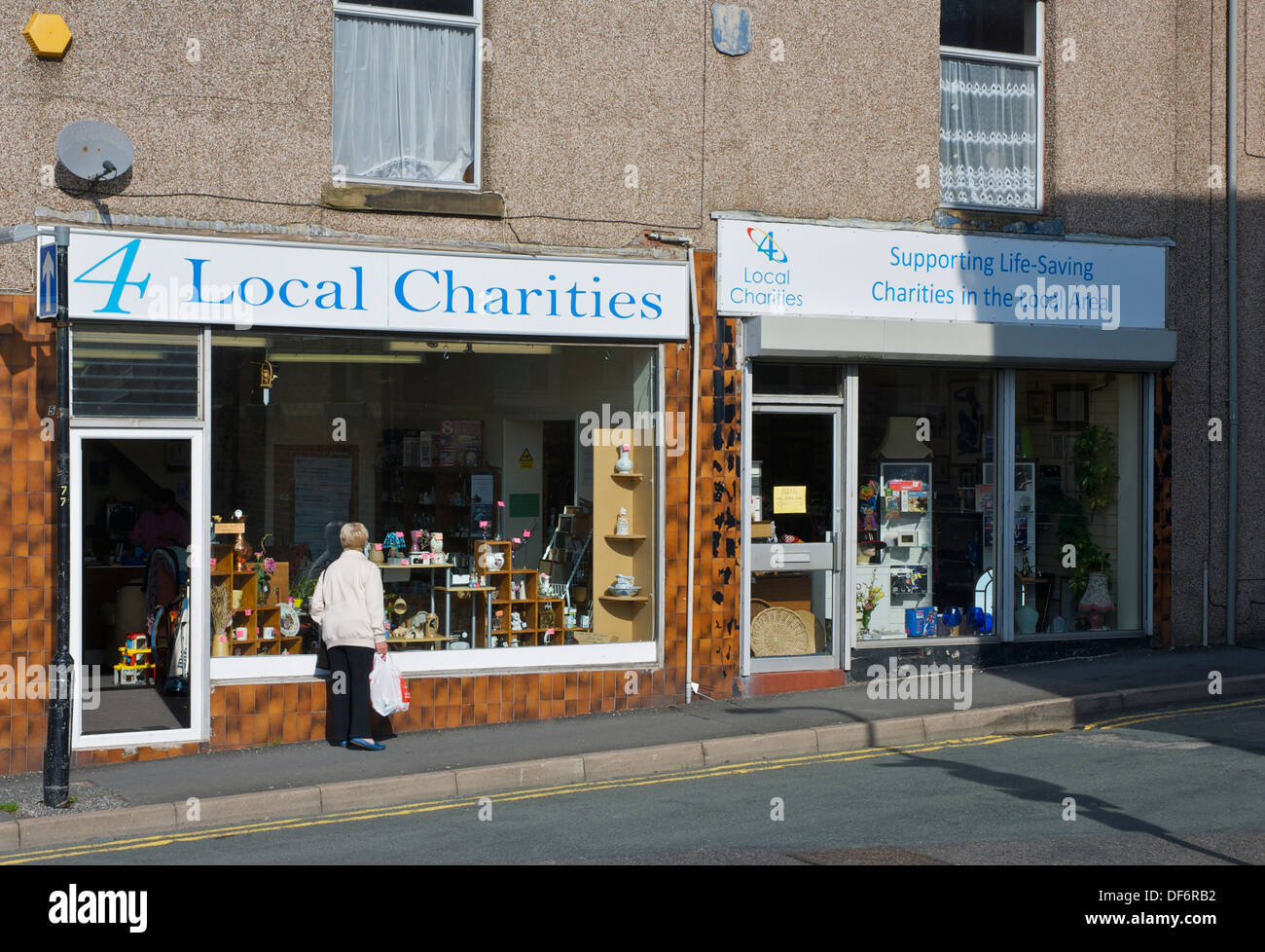 Woman looking into charity shop in Barrow-in-Furness, Cumbria, England ...