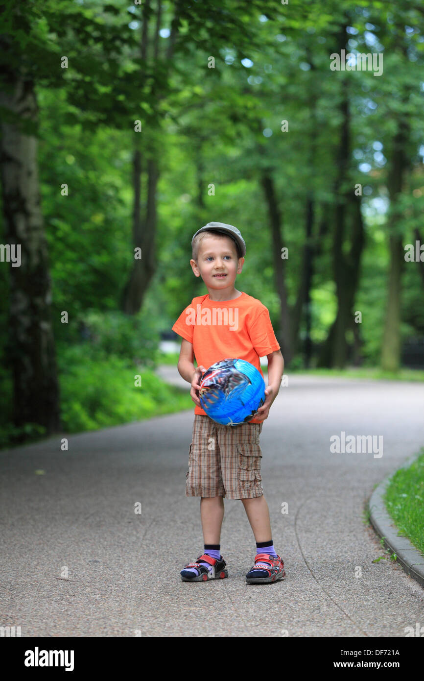 Boy in action young kid playing with ball in park outdoors. Healthy ...