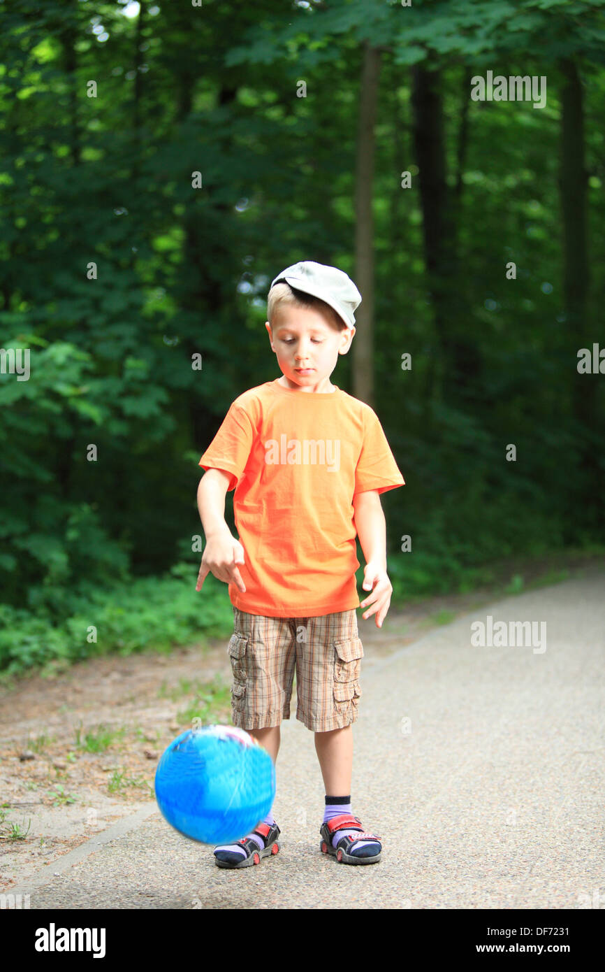 Boy in action young kid playing with ball in park outdoors. Healthy ...