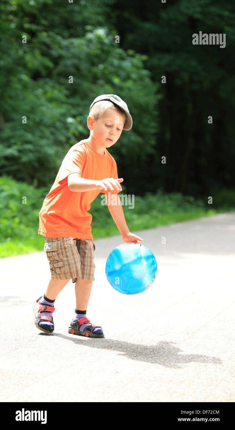 Boy in action young kid playing with ball in park outdoors. Healthy ...