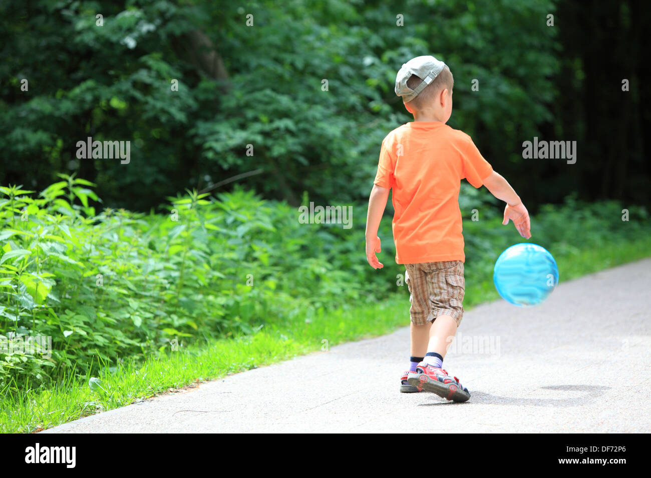 Boy in action young kid playing with ball in park outdoors. Healthy ...