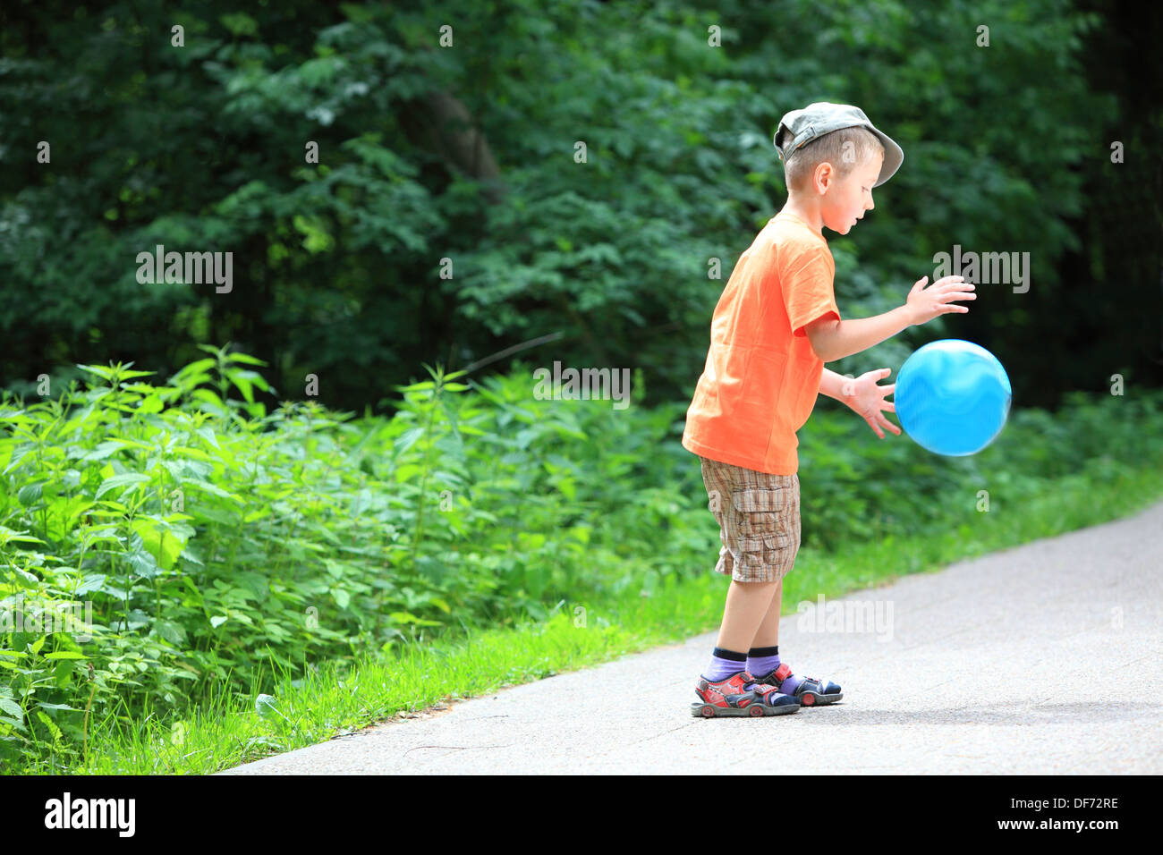 Boy in action young kid playing with ball in park outdoors. Healthy ...