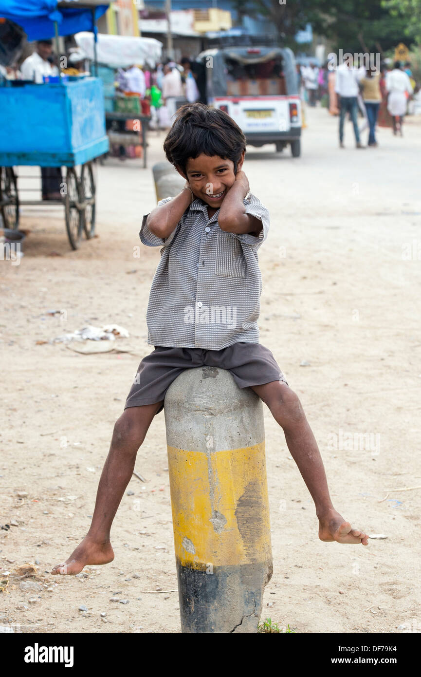 Happy smiling lower caste Indian boy sitting on a post in an indian ...