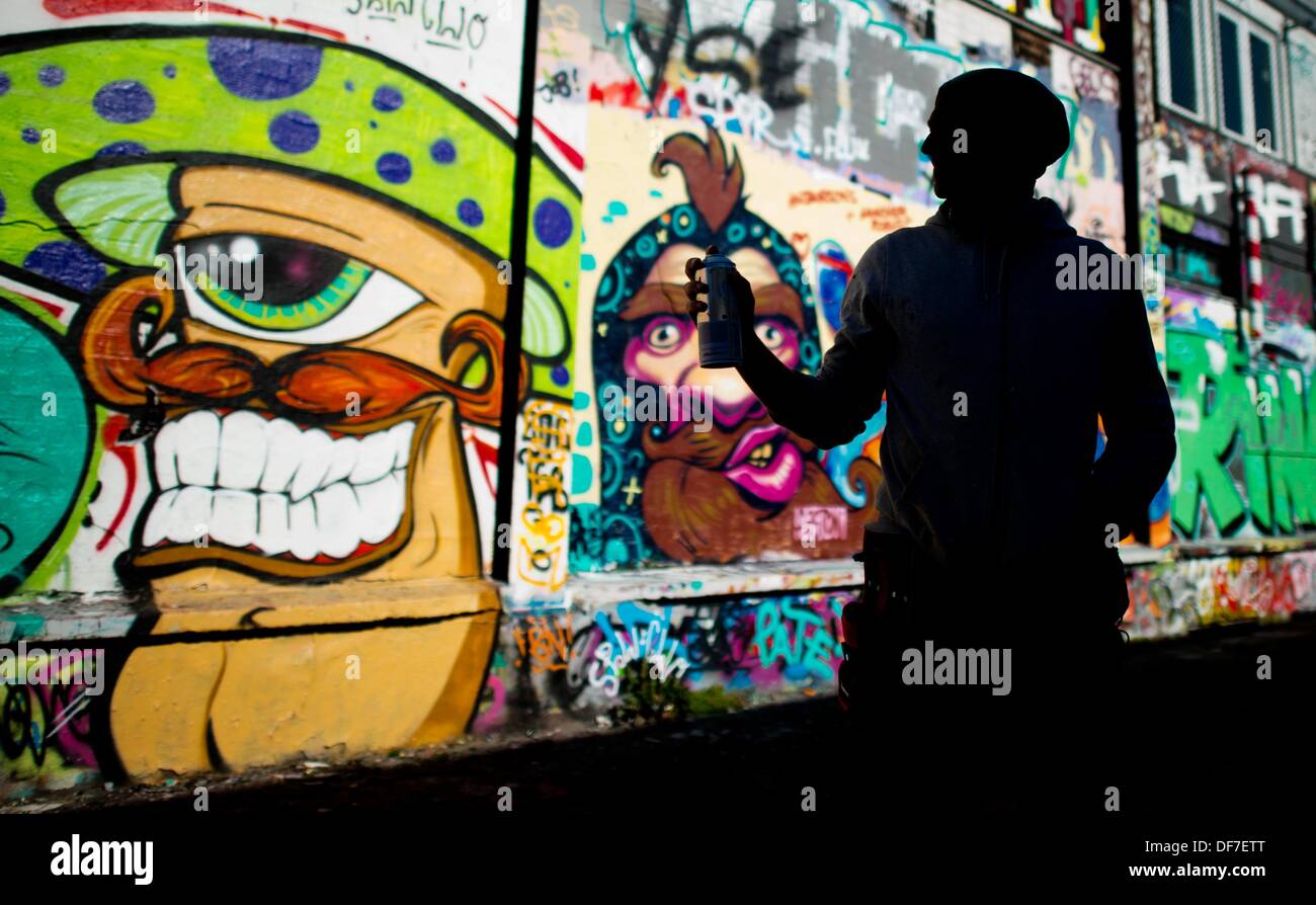 An artist sprays graffiti onto a wall with other graffiti in Hanover ...