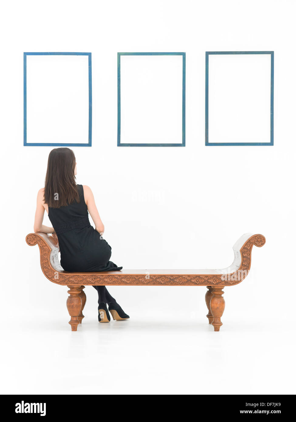 back view of woman sitting on a bench looking at empty frames displayed ...