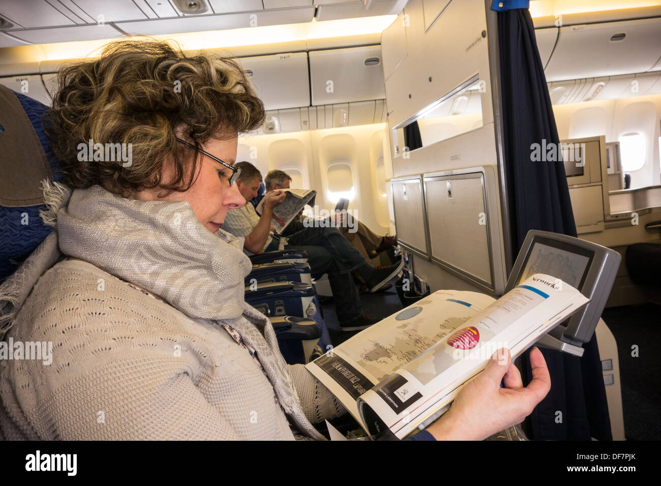 A woman passenger reading in-flight magazine on airplane Stock Photo ...