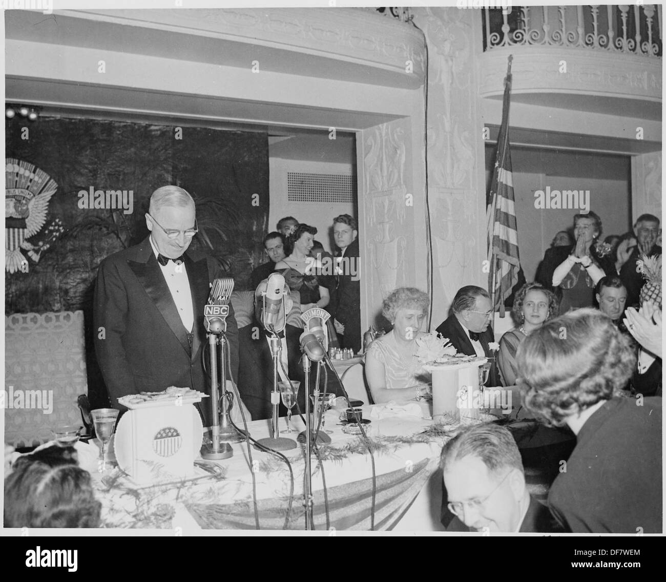 President Harry S. Truman is standing at a microphone during a dinner ...