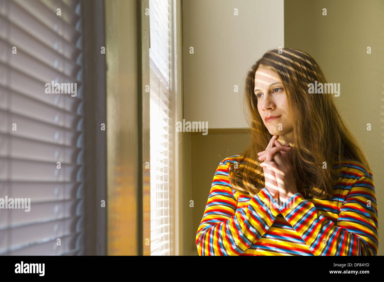 Young woman standing by her window Stock Photo - Alamy