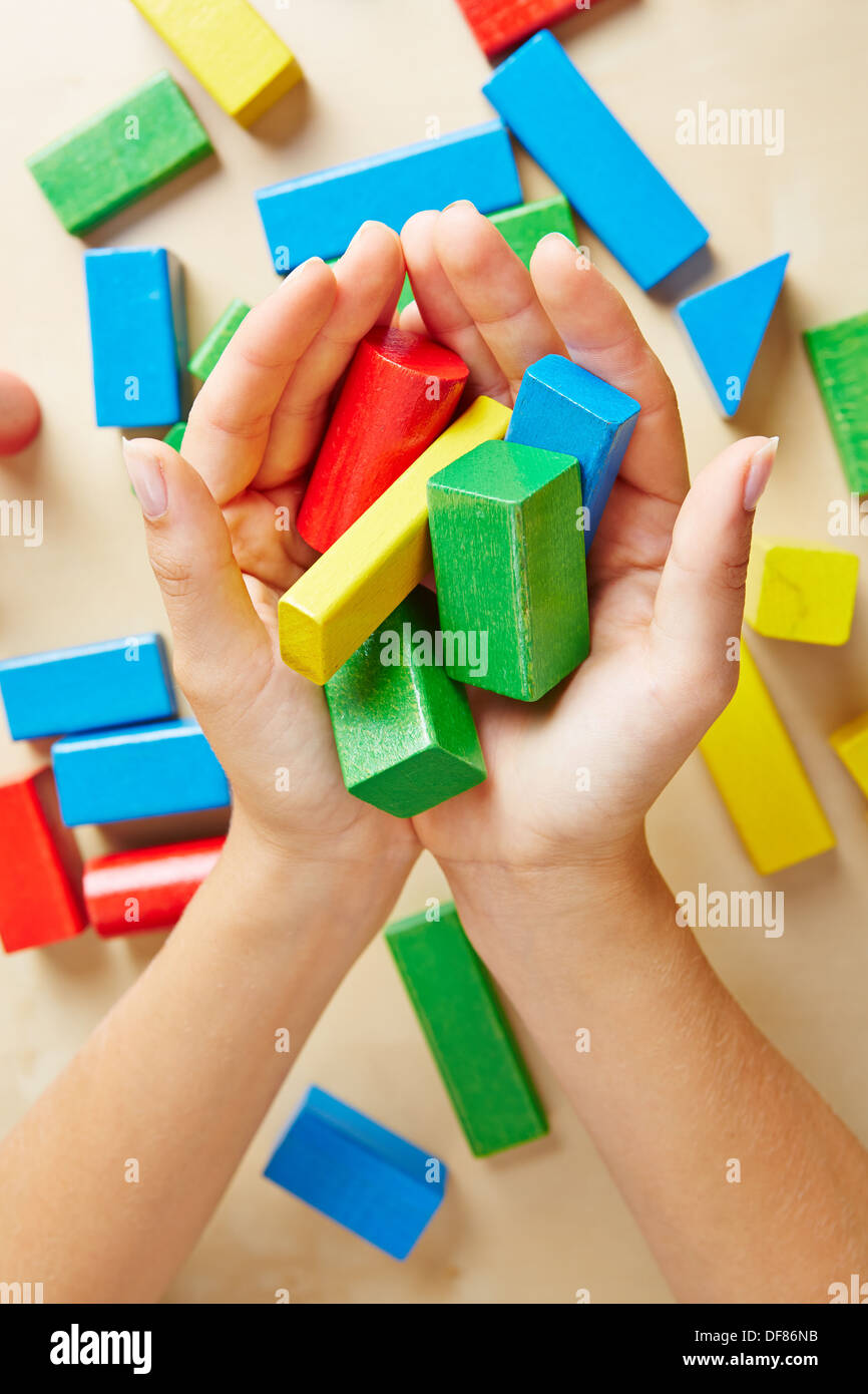 Two hands holding many colorful wooden building blocks Stock Photo - Alamy