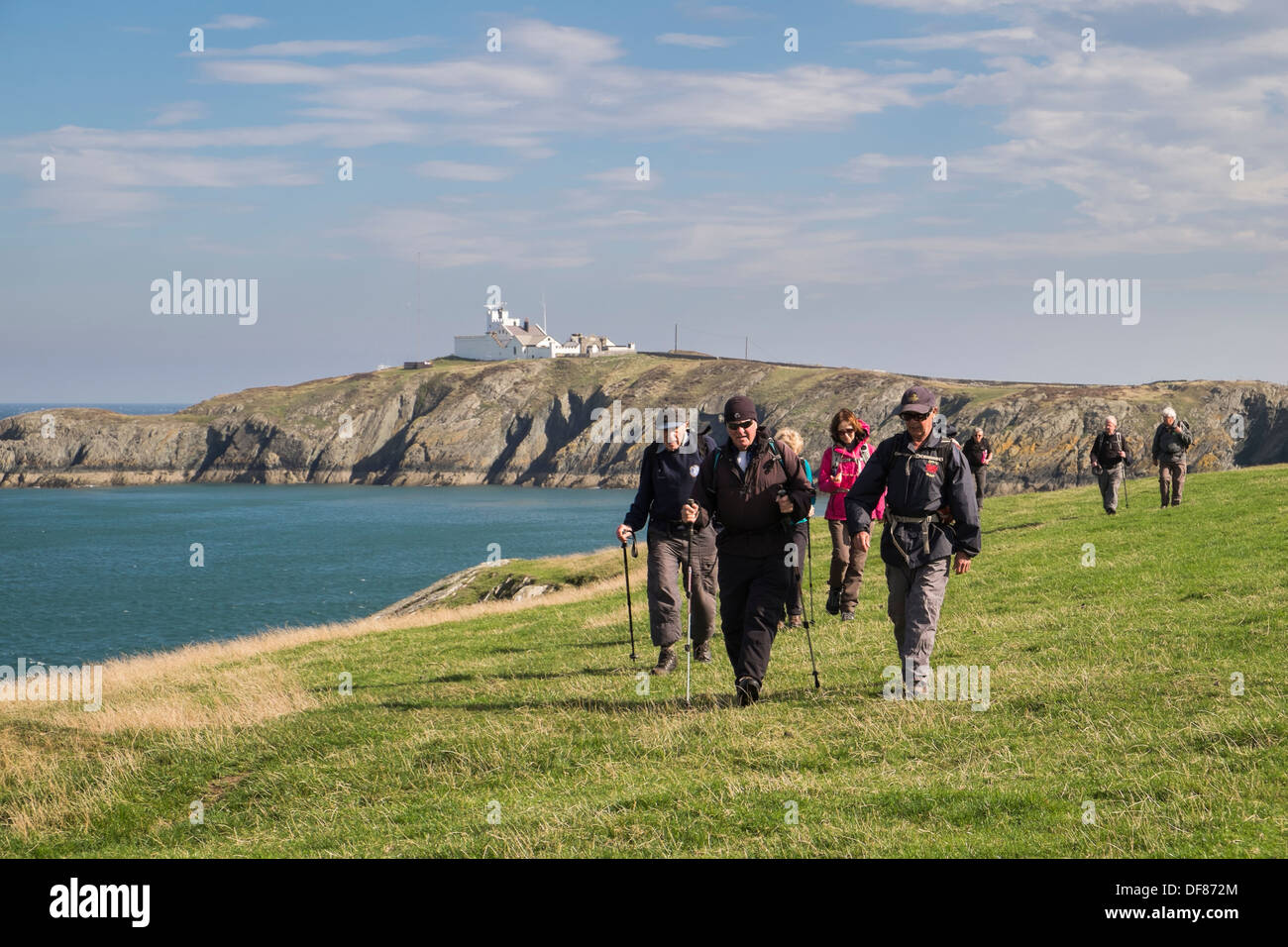 Ramblers group of walkers walking on coastal path with Point Lynas ...