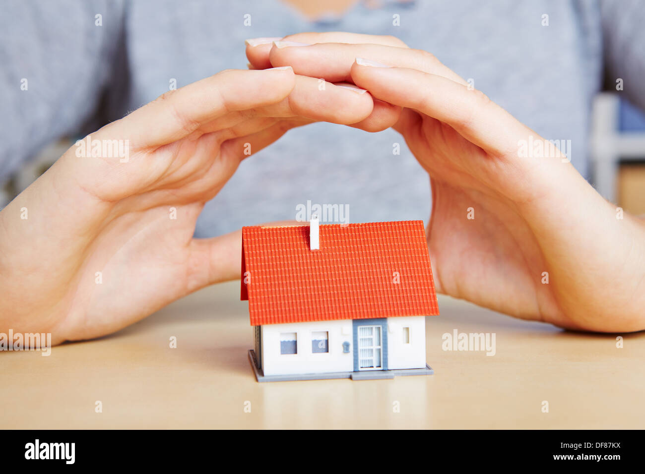 Two hands protecting a little house like an insurance Stock Photo - Alamy