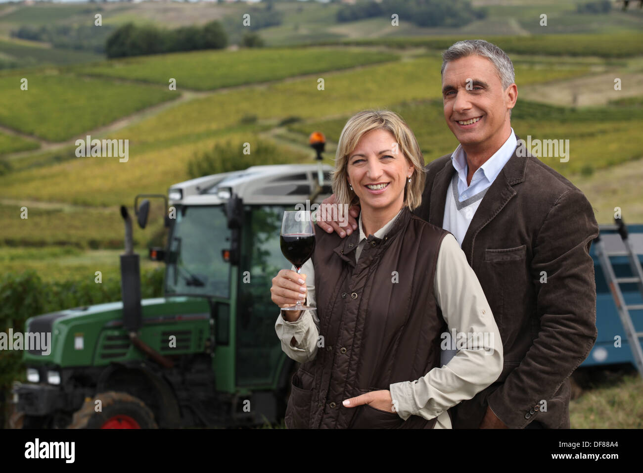 Farming couple stood in field in front of tractor Stock Photo - Alamy