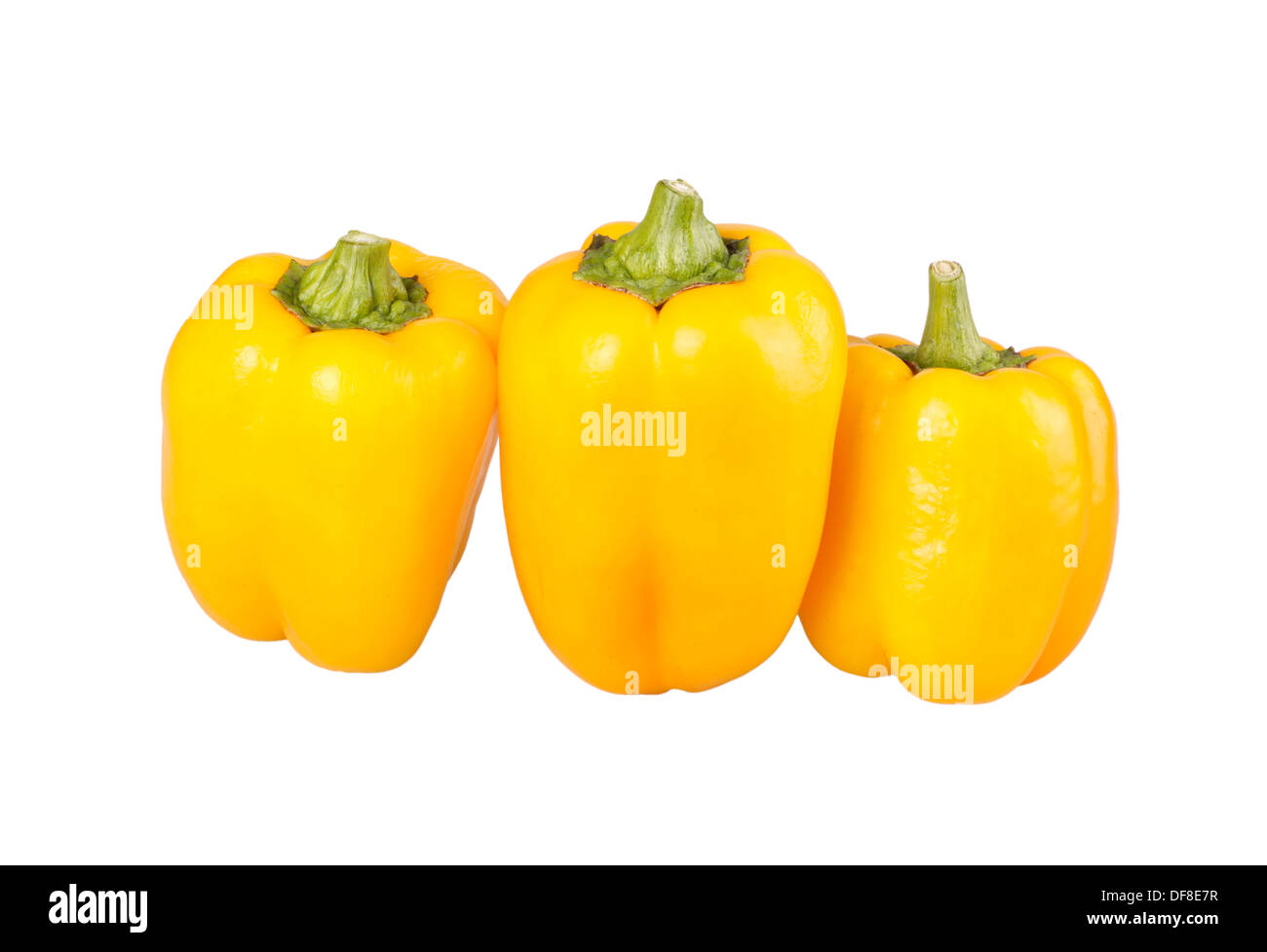 Three yellow bell peppers (Capsicum annuum) isolated against a white ...