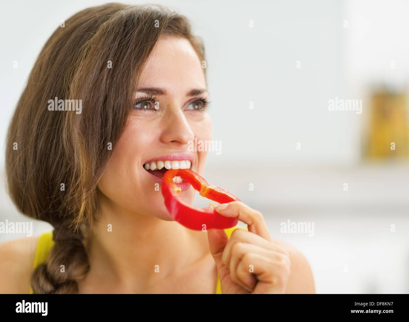 Happy young woman having a bite of red bell pepper Stock Photo - Alamy