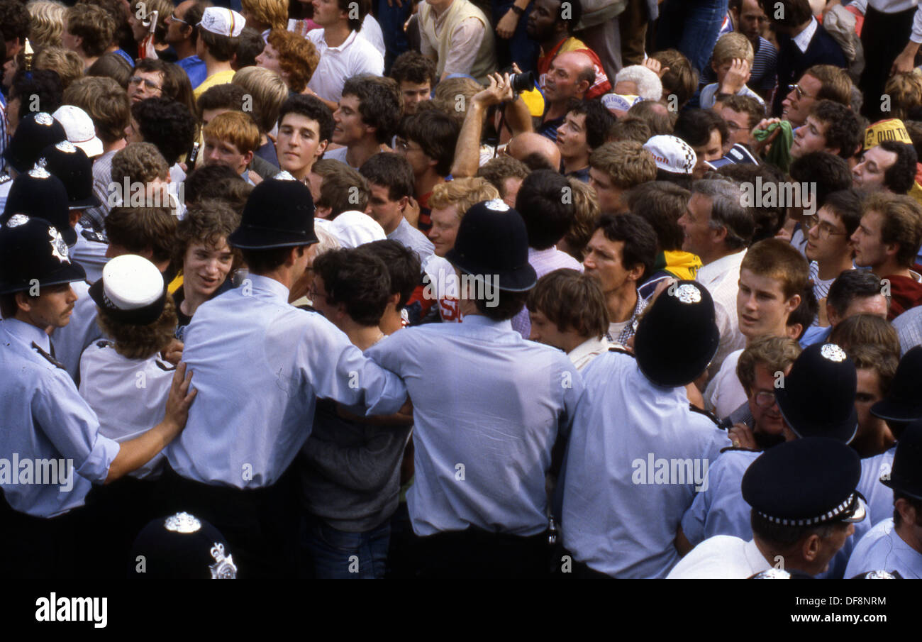 1980s, crowd control, a line of British policemen earing helmets keep a ...