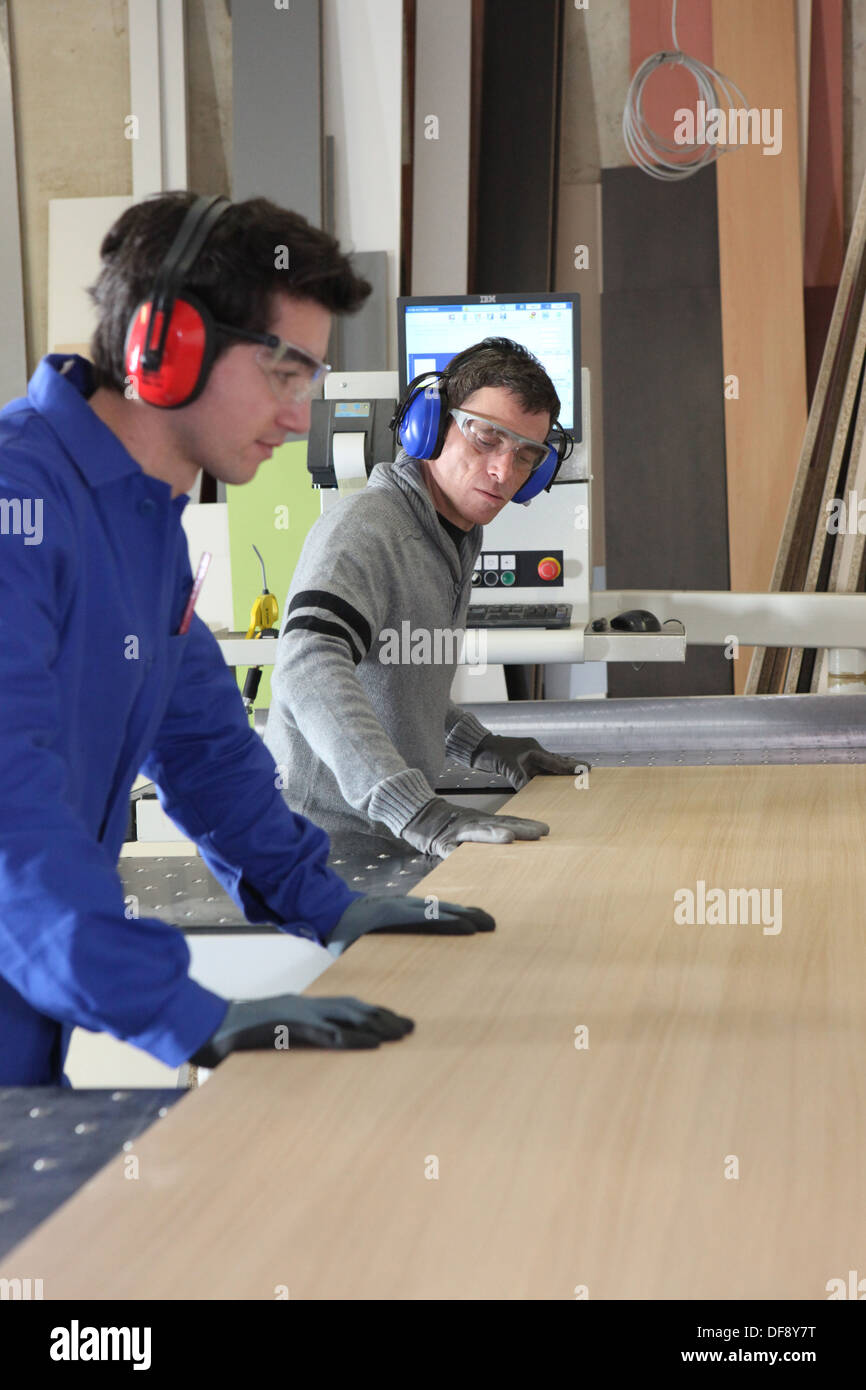 Two workers using factory saw Stock Photo - Alamy
