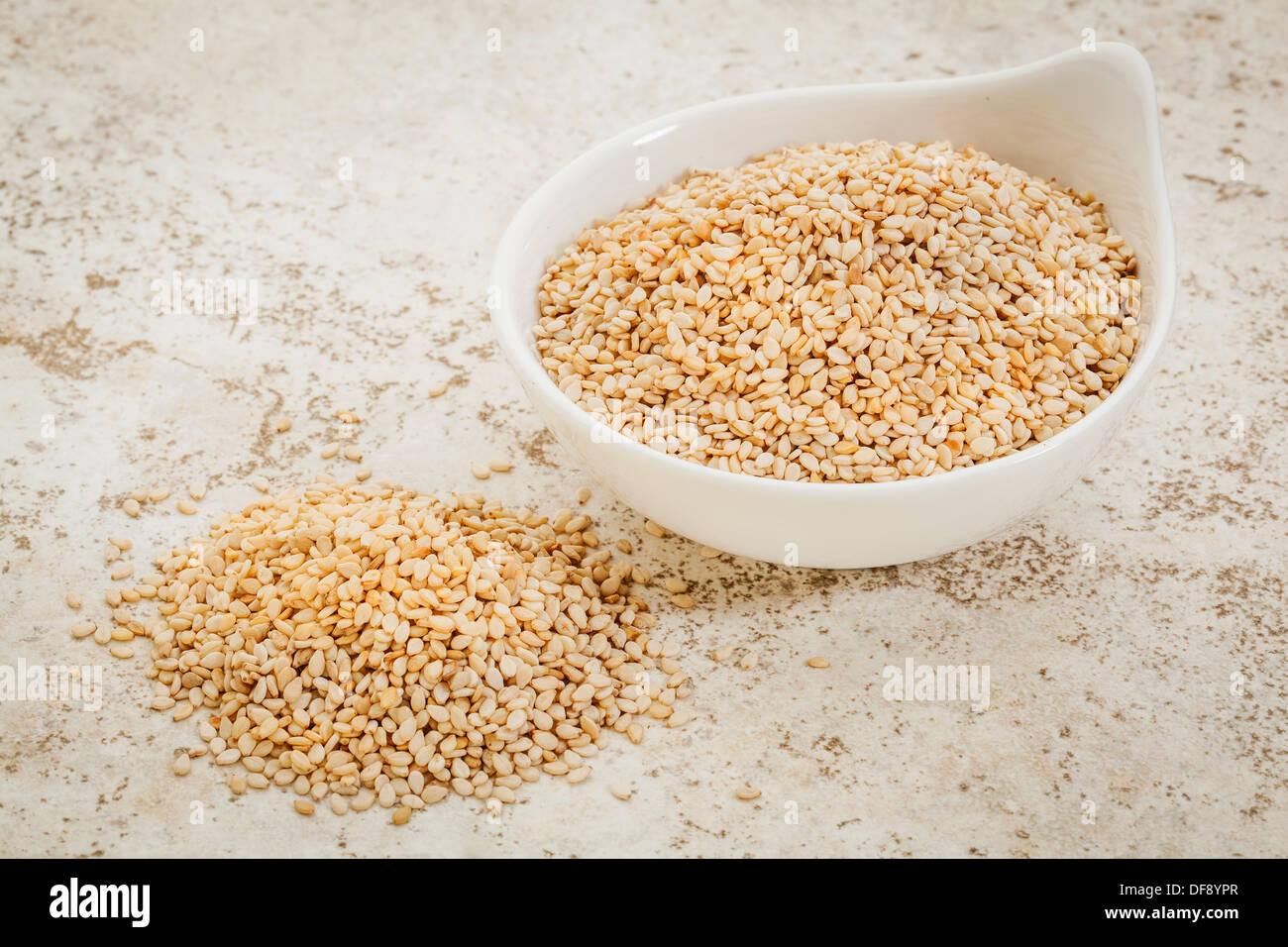 small ceramic bowl of unhulled sesame seeds against a ceramic tile ...