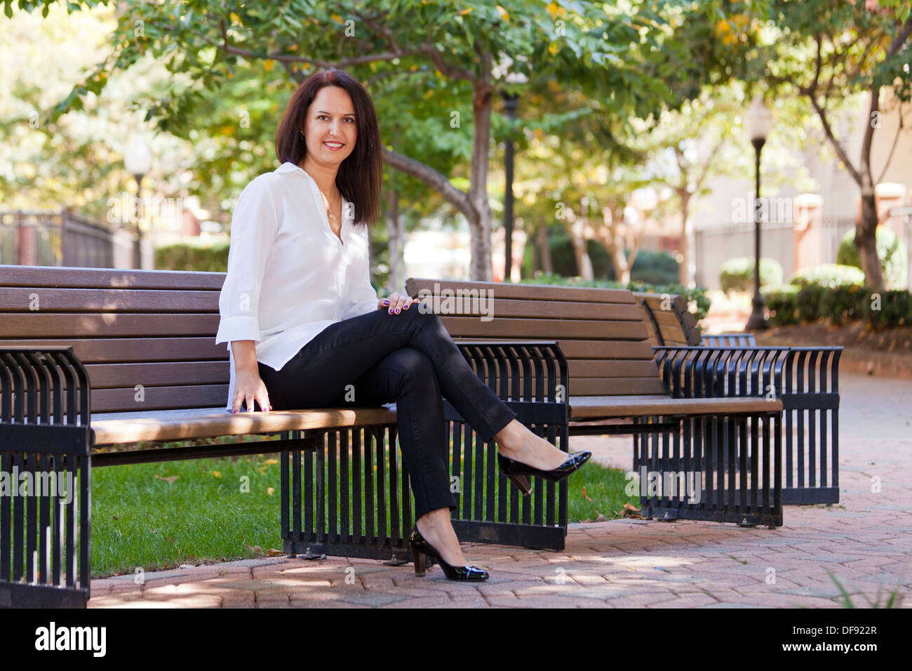 Portrait of woman sitting on park bench Stock Photo - Alamy
