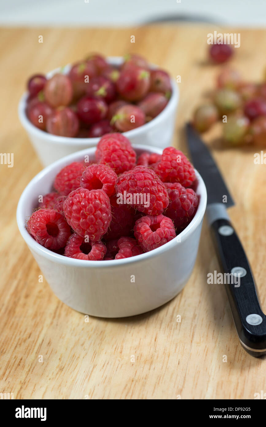 Small bowls of soft summer fruit - raspberries and red gooseberries ...
