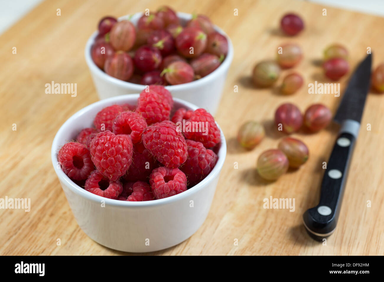Small bowls of soft summer fruit - raspberries and red gooseberries ...