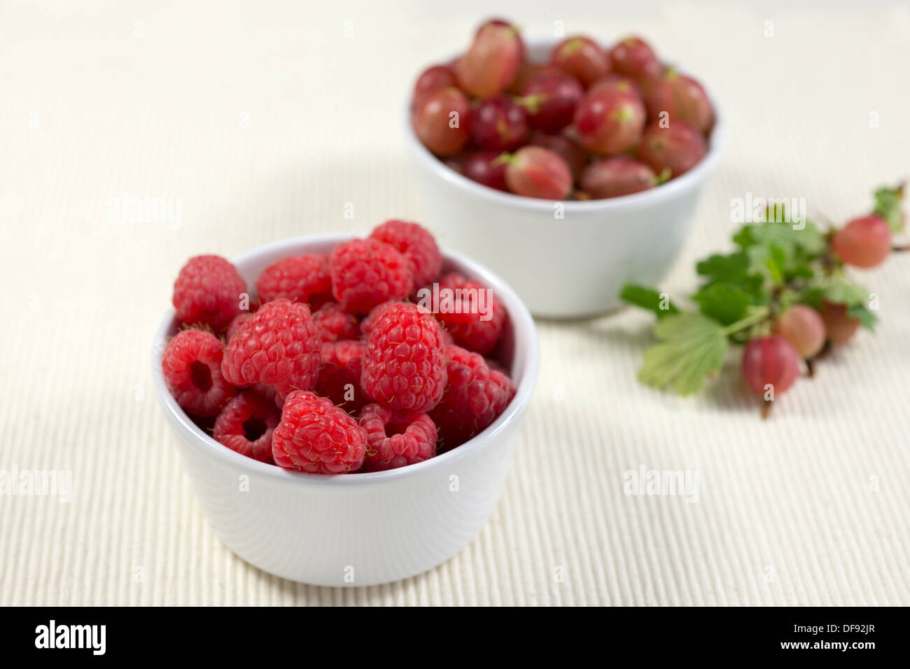 Small bowls of soft summer fruit - raspberries and red gooseberries ...