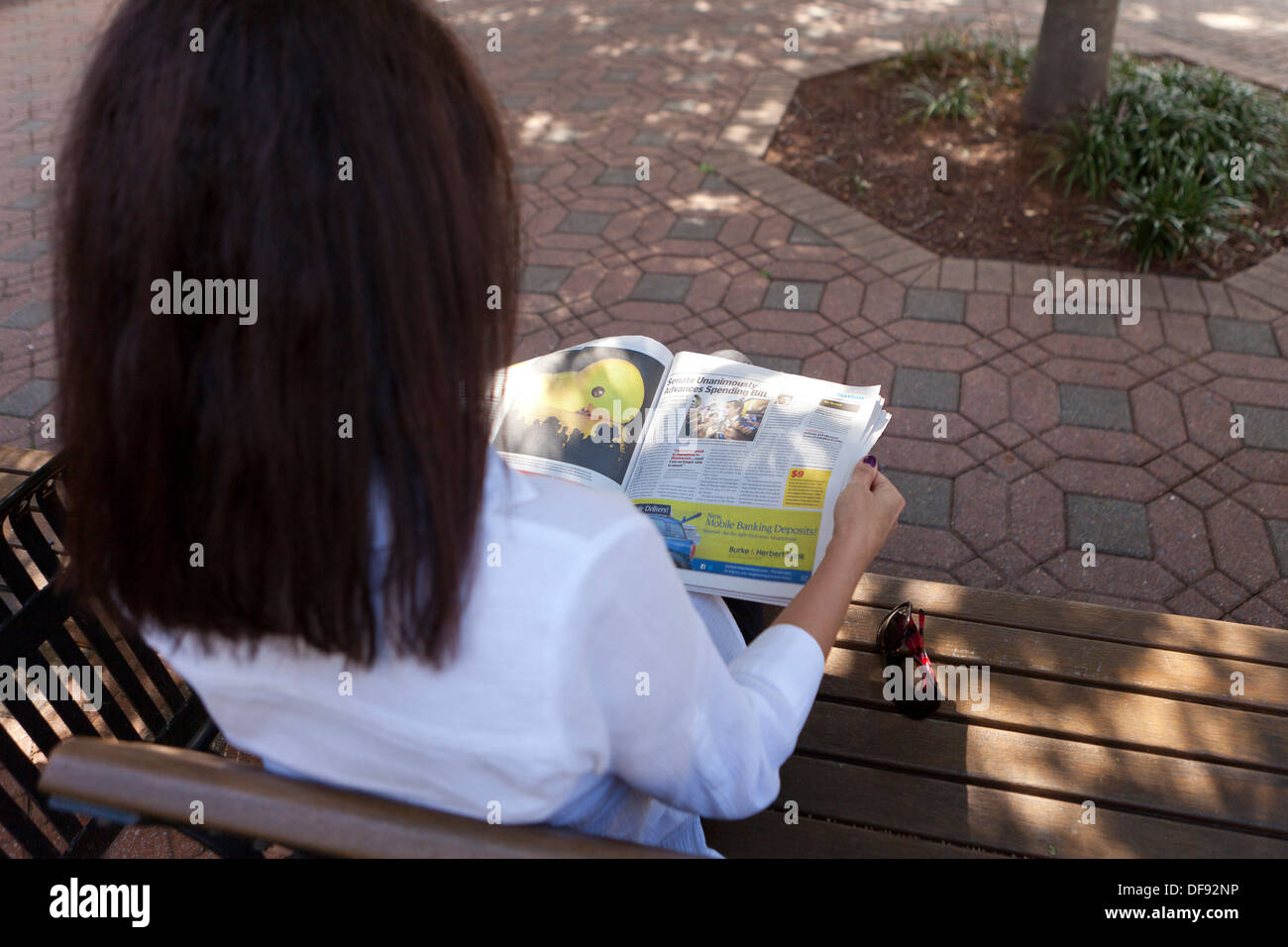 Woman reading newspaper outdoor bench Stock Photo - Alamy