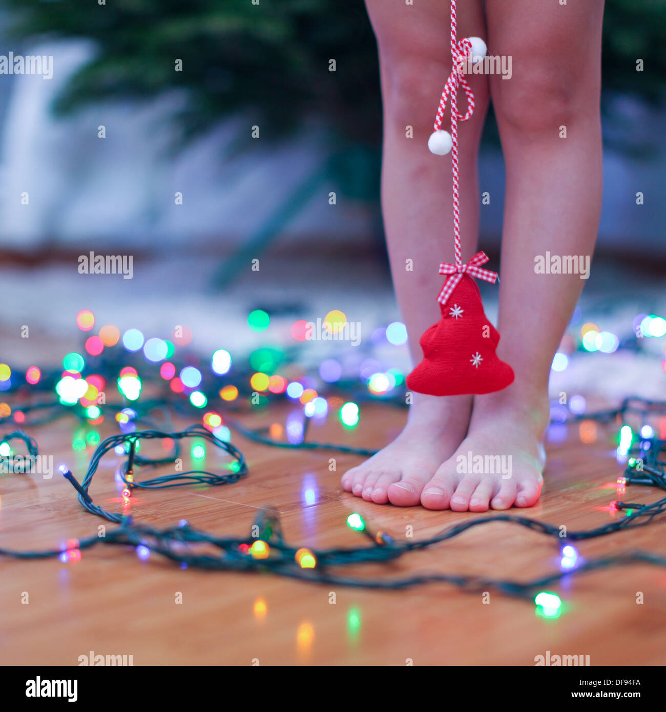 Little red tree in the hands of charming cute girl at bright lights ...