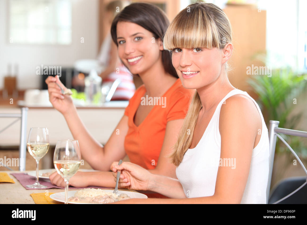 Two girls eating in the kitchen Stock Photo - Alamy