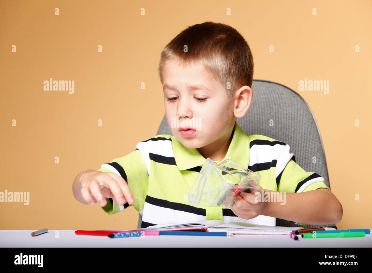 little boy drawing with color pencils on orange background Stock Photo ...