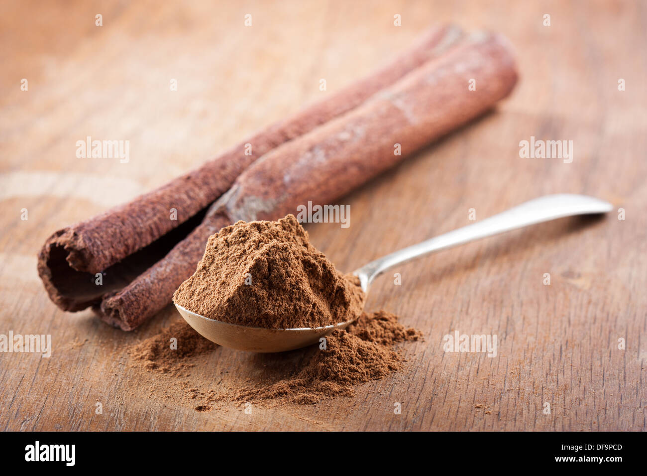 Cinnamon powder on a silver spoon with a stick of natural cinnamon on ...