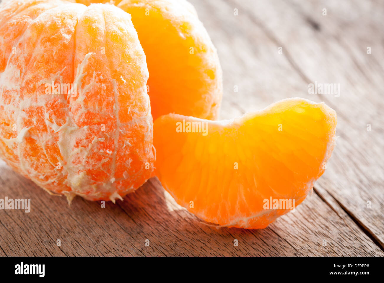 Peeled tangerine with a slice on a wooden table close-up Stock Photo ...