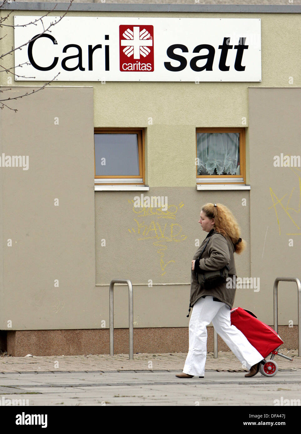 A woman walks past the "Carisatt" (a blend of "Caritas" charity and ...