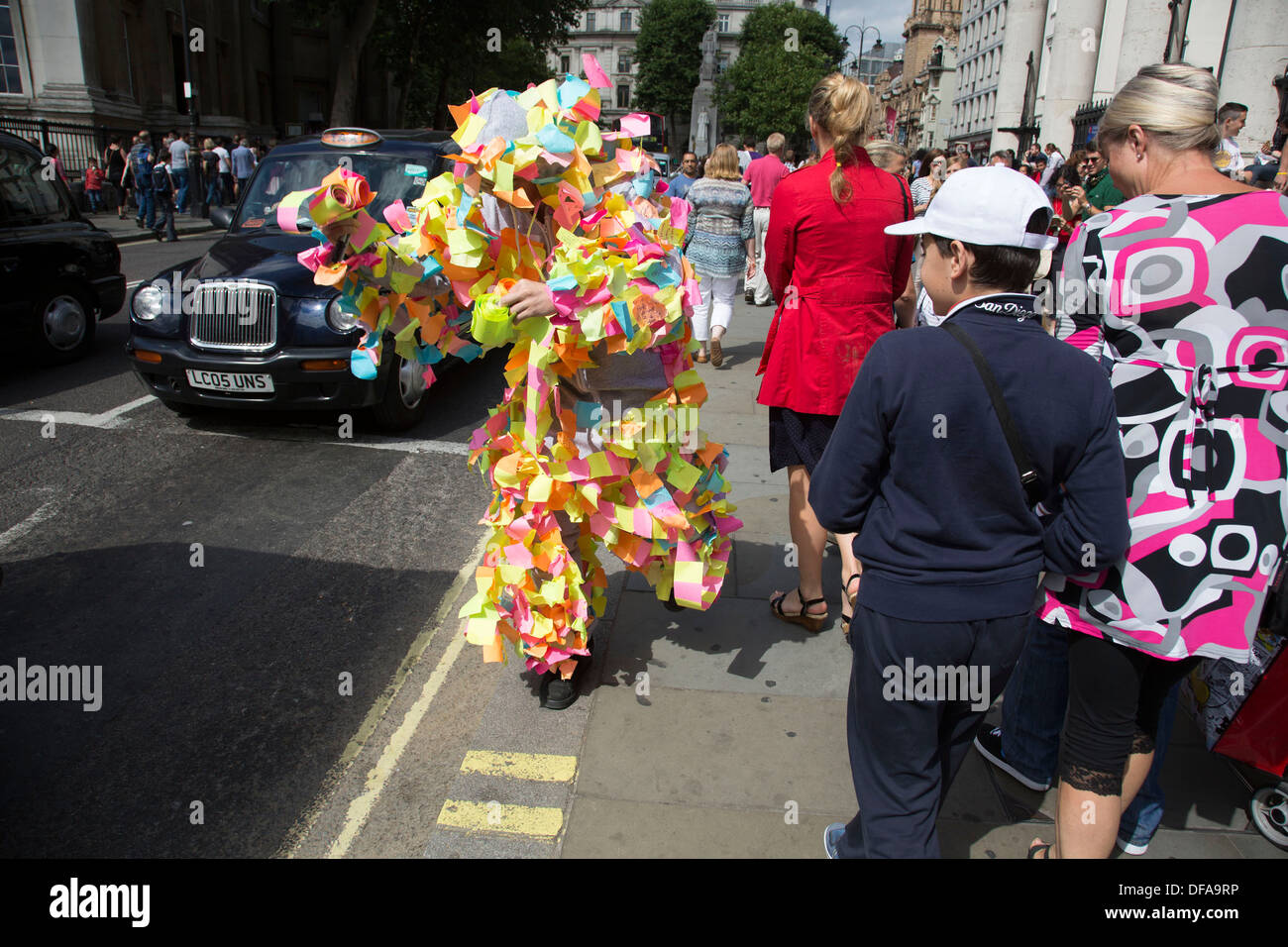 Man dressed up in hundreds of Post-it notes walks along a street in ...